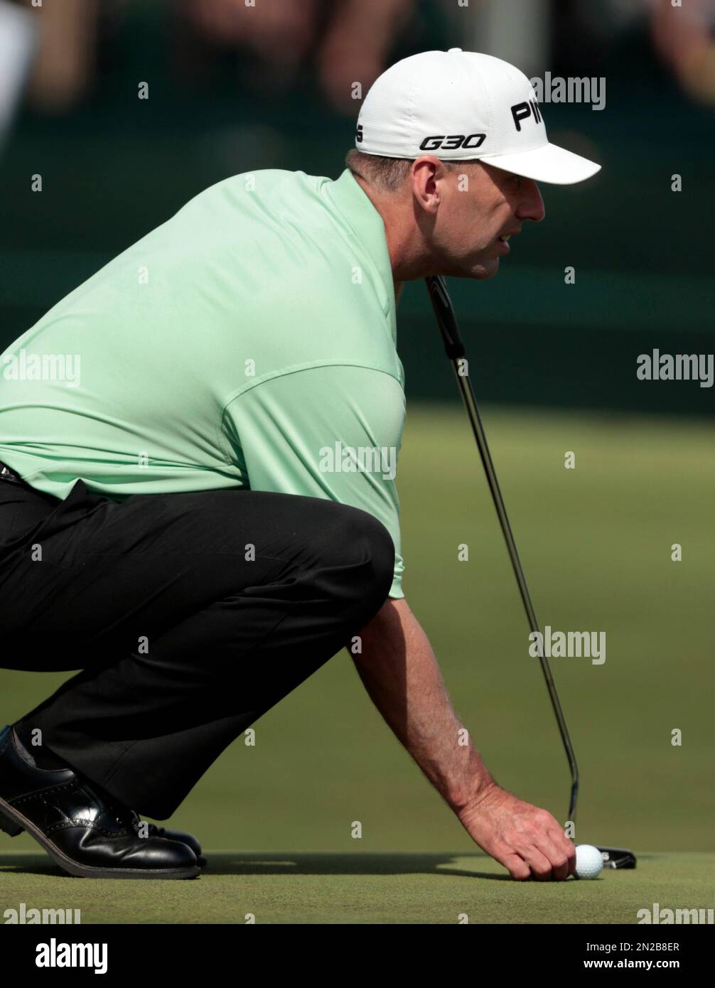 Kevin Sutherland places his ball as he prepares to putt on the 18th ...