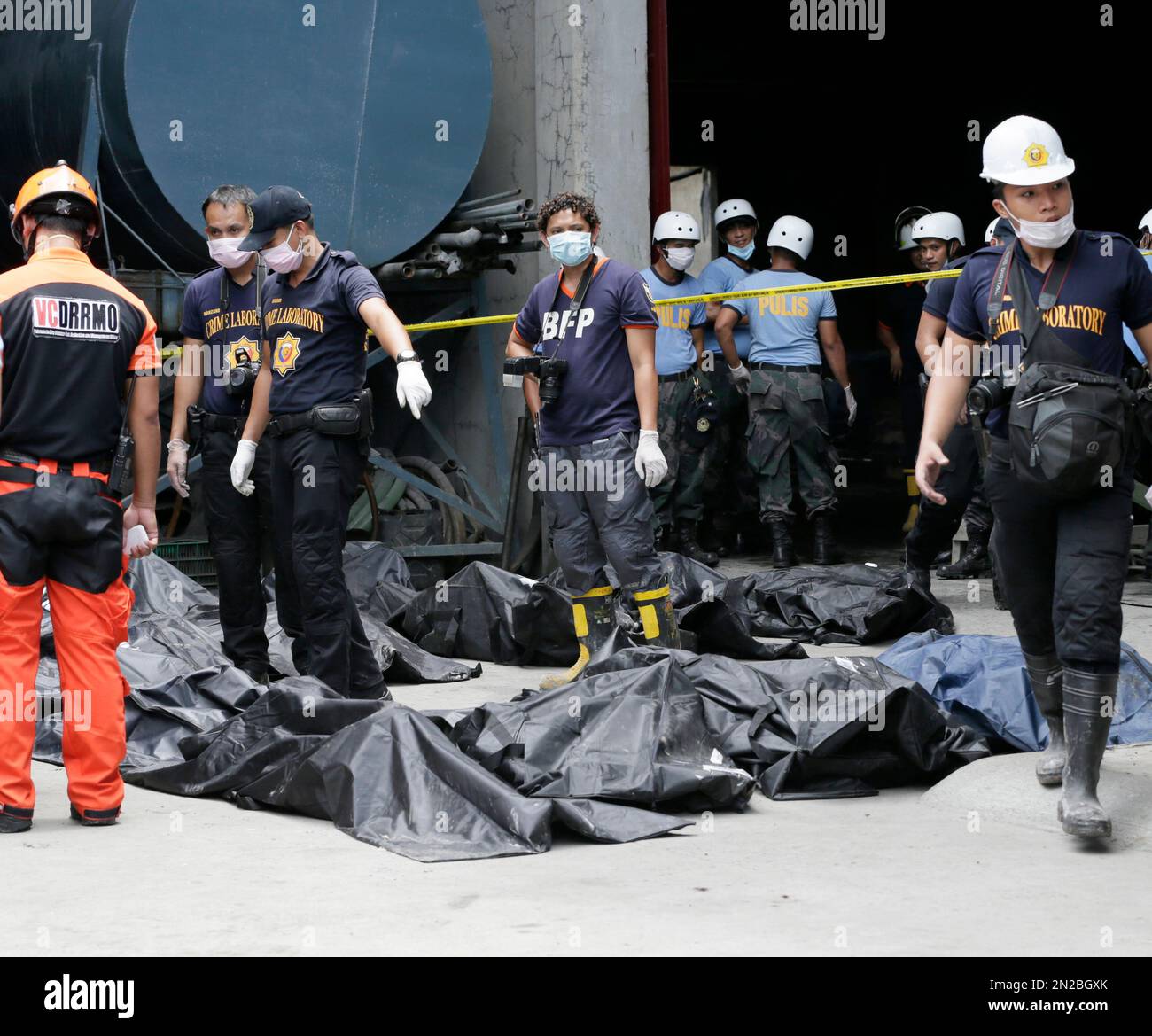 Philippine National Police stand beside the body bags of fire victims ...