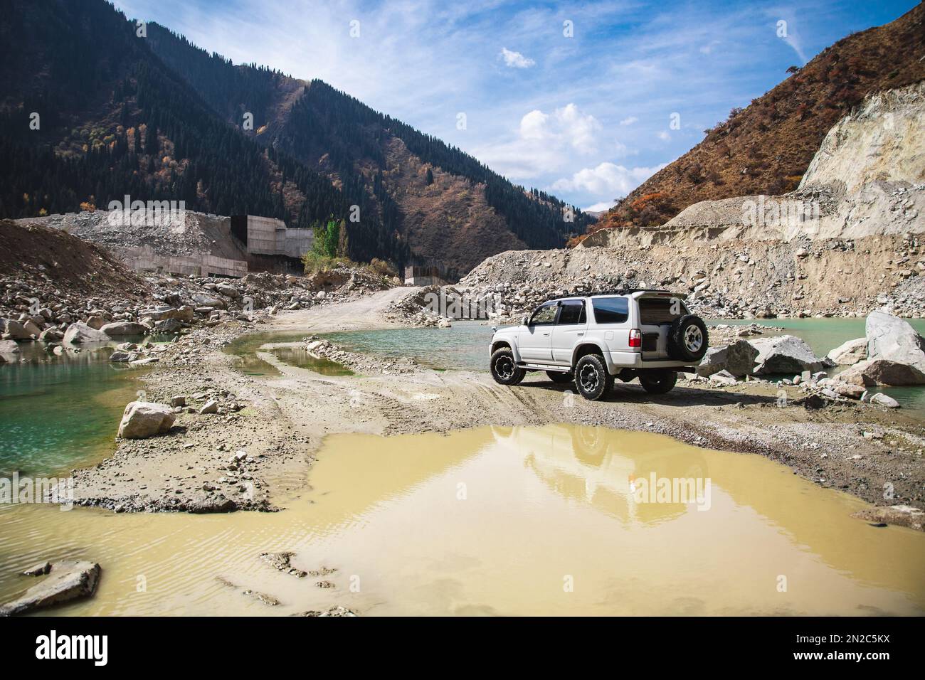 White off-road car in travel of scenic mountains with river and lake ...