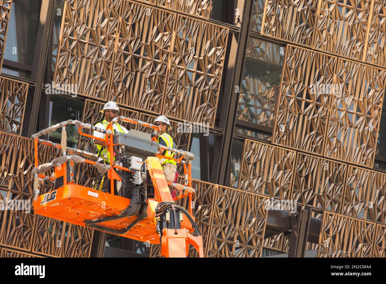 Construction workers install the bronze colored cladding that will form ...