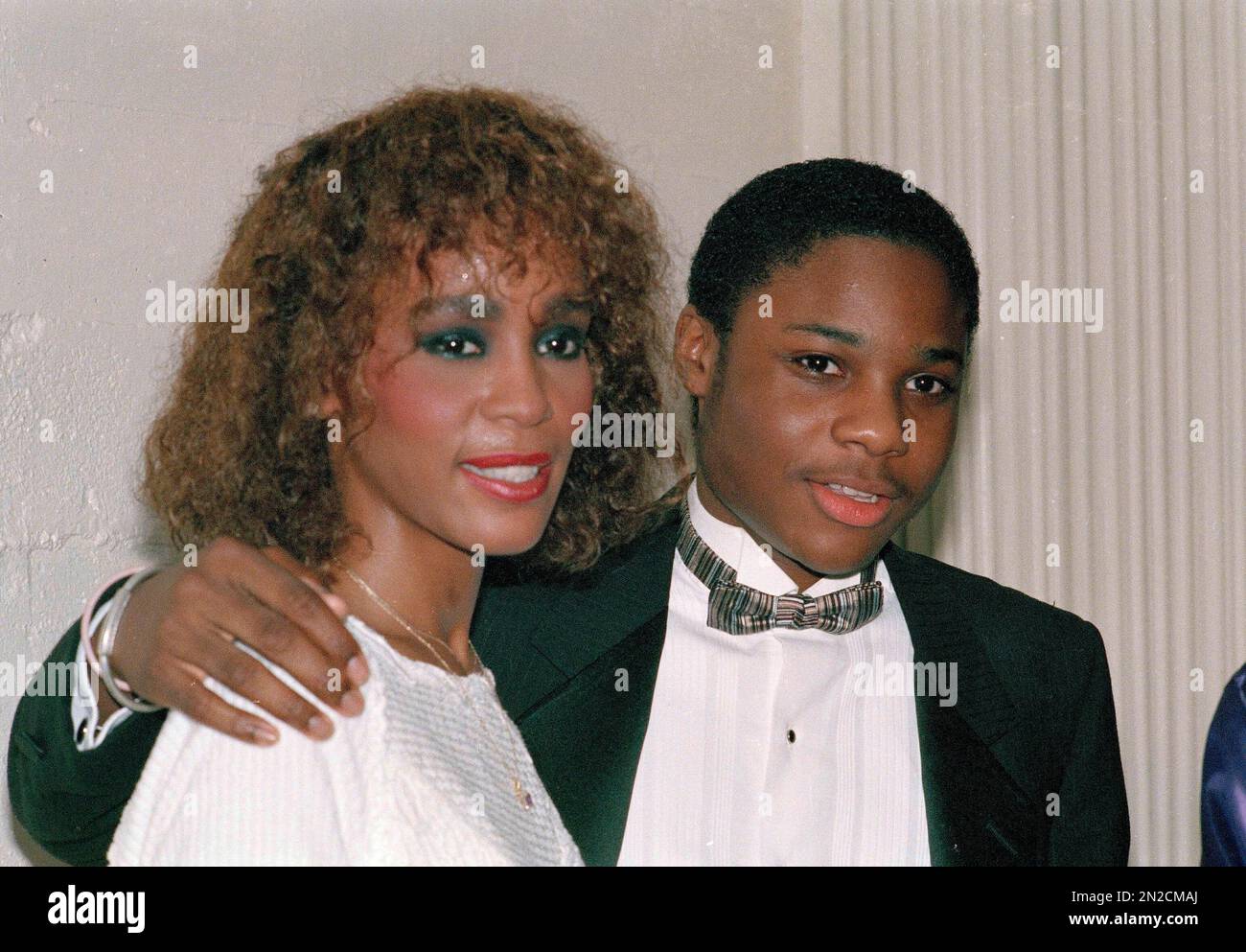 Actress and singer Whitney Houston receives a congratulatory hug from ...