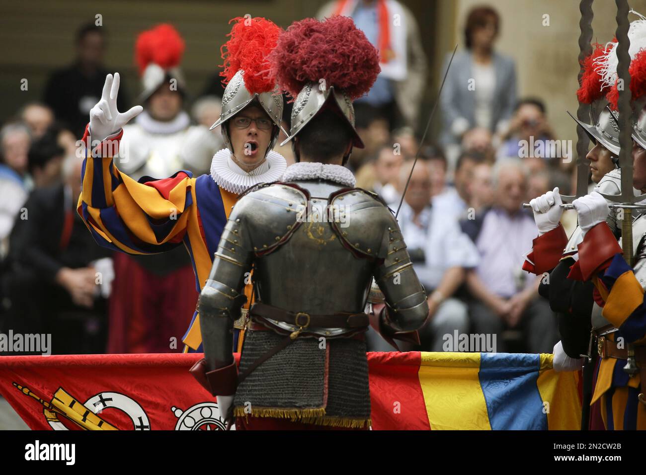 Vatican Swiss guards, one of them, left, holding up his right arm and ...