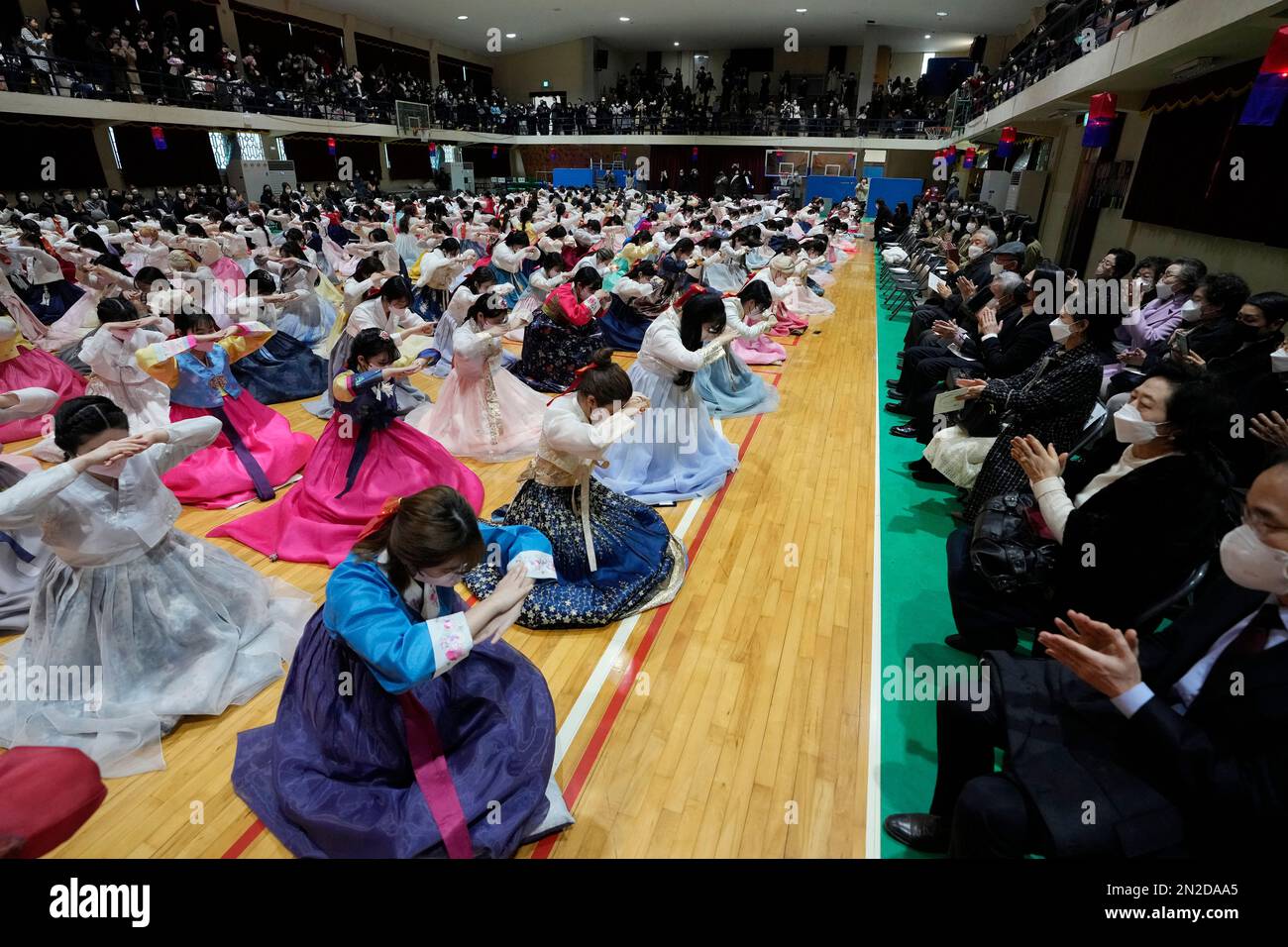 High school seniors clad in traditional attire bow to their teachers ...