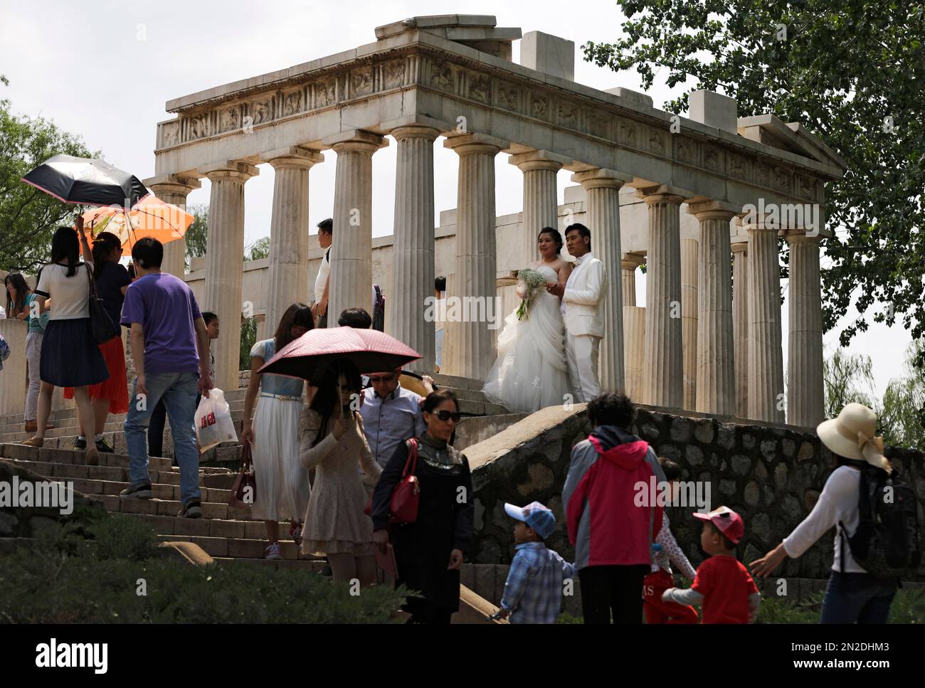 Visitors walk past a bride and groom pose for wedding photos at the ...