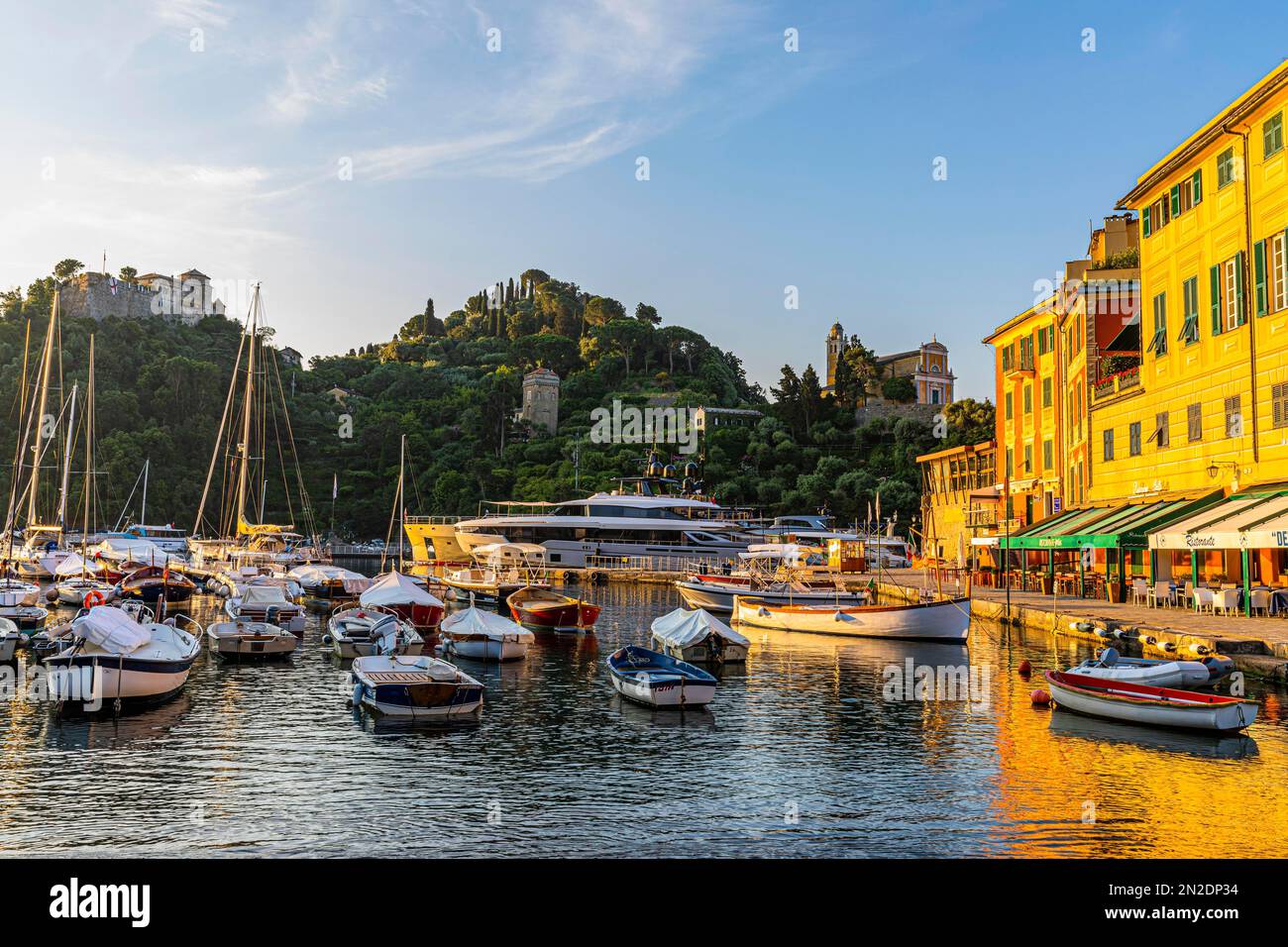 Boats anchored in the harbour of Portofino in the morning light, behind ...