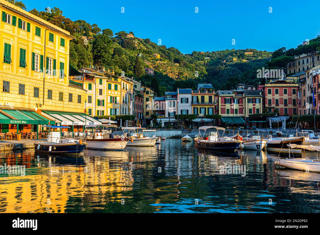 Boats anchored in the harbour of Portofino, behind them pastel-coloured ...