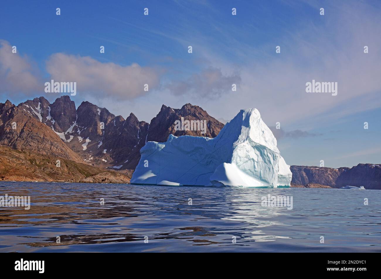 Giant iceberg jutting out of the water, barren coastal landscape ...