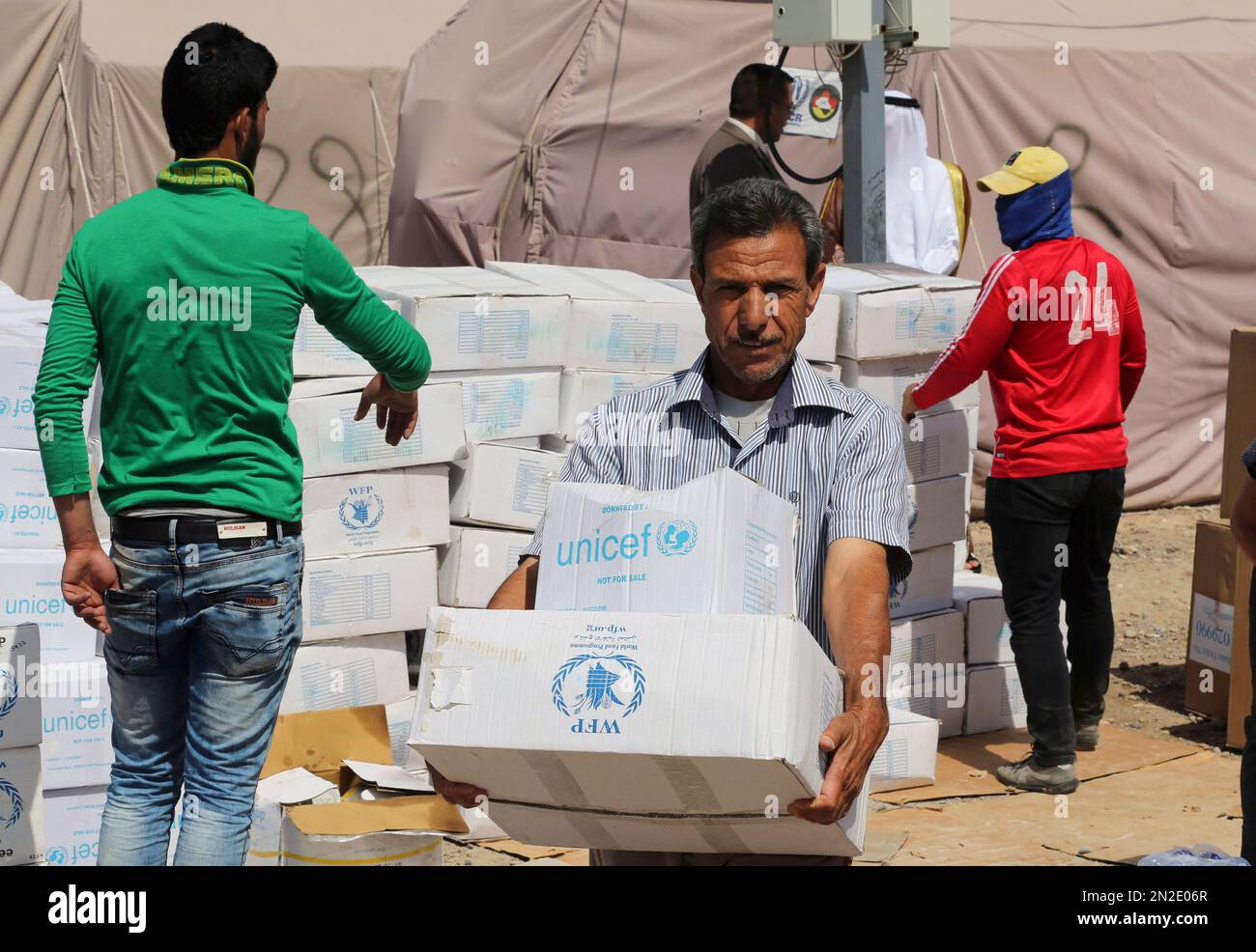 A man carries boxes of humanitarian aid at a camp set up for people ...