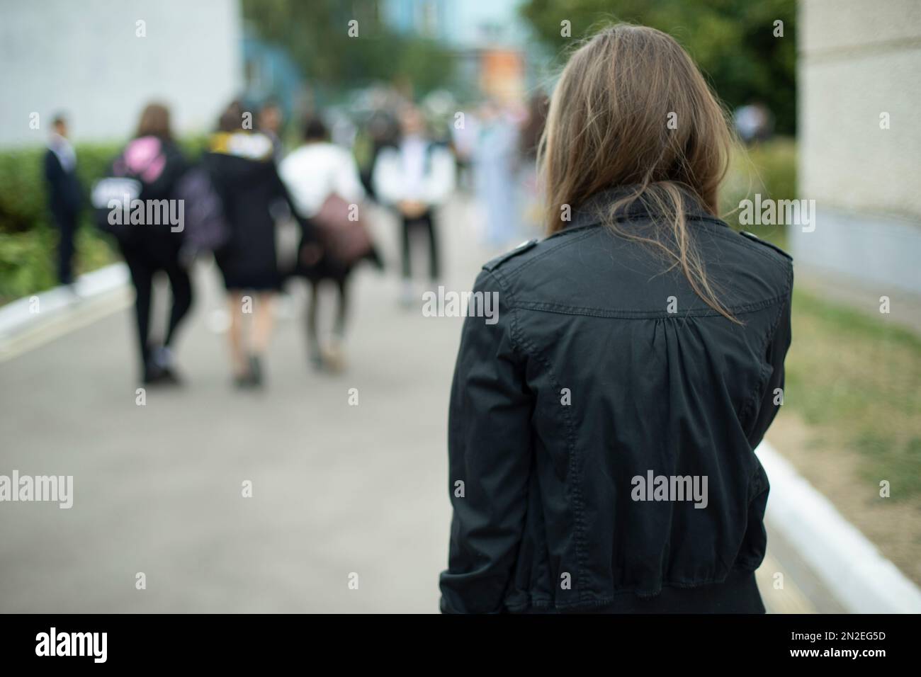 Girl in black jacket in schoolyard. Girl is coming home from school ...