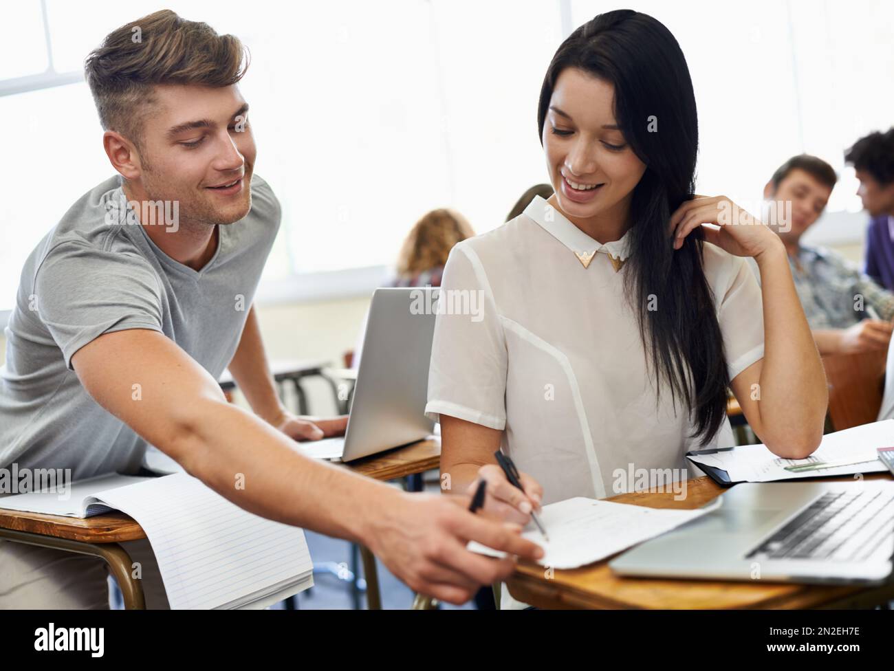 Helping out a classmate. Two students helping each other in a varsity ...