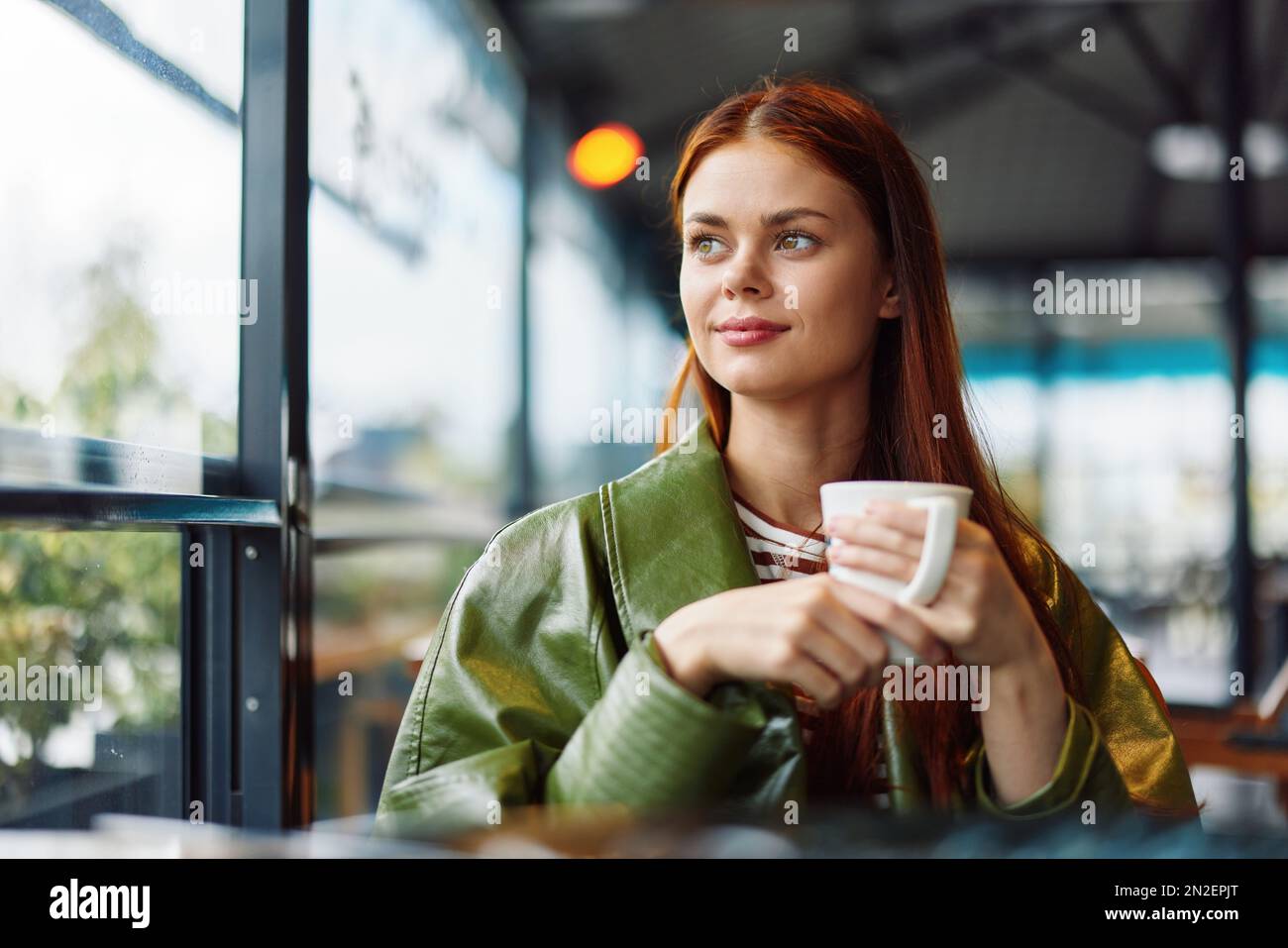 Portrait of a woman influencer drinking a drink from a mug in a cafe ...