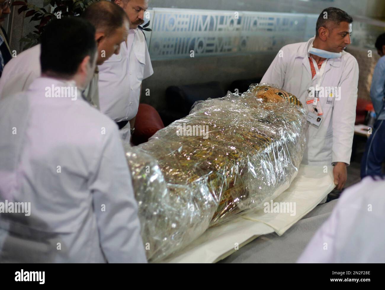 Egyptian policemen and antiquities officials carry the wooden coffin of ...