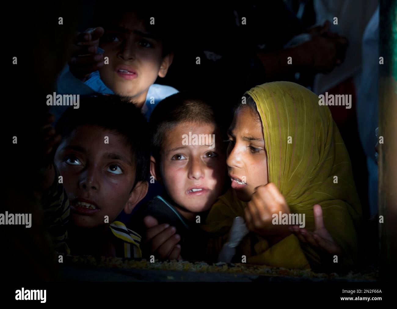 Pakistani children wait to receive food donations at a distribution ...