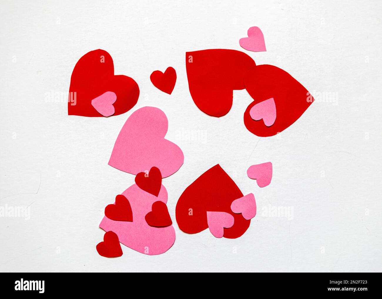 Red and pink paper hearts of different sizes on a light background ...