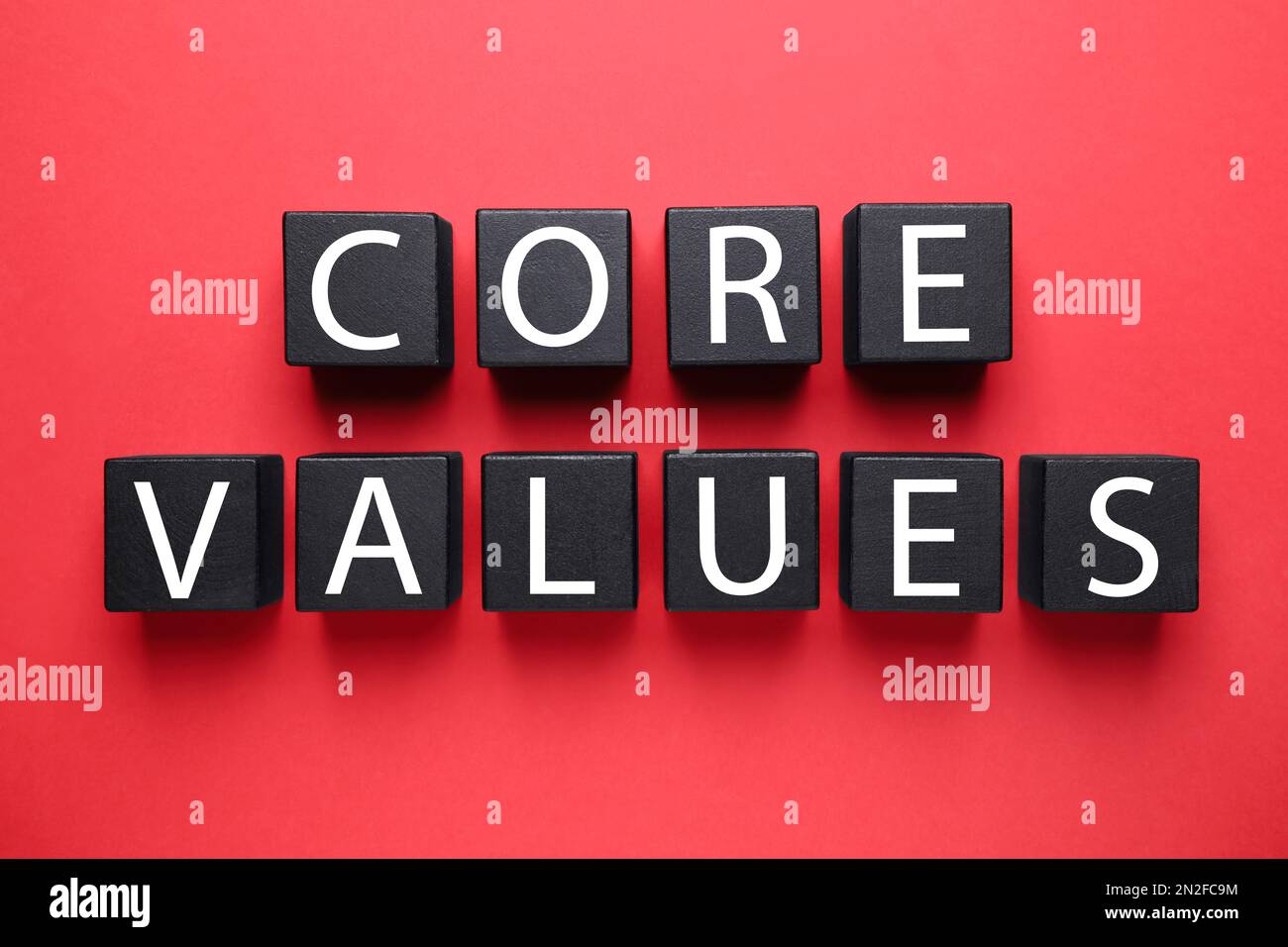 Black wooden cubes with phrase CORE VALUES on red background, flat lay ...