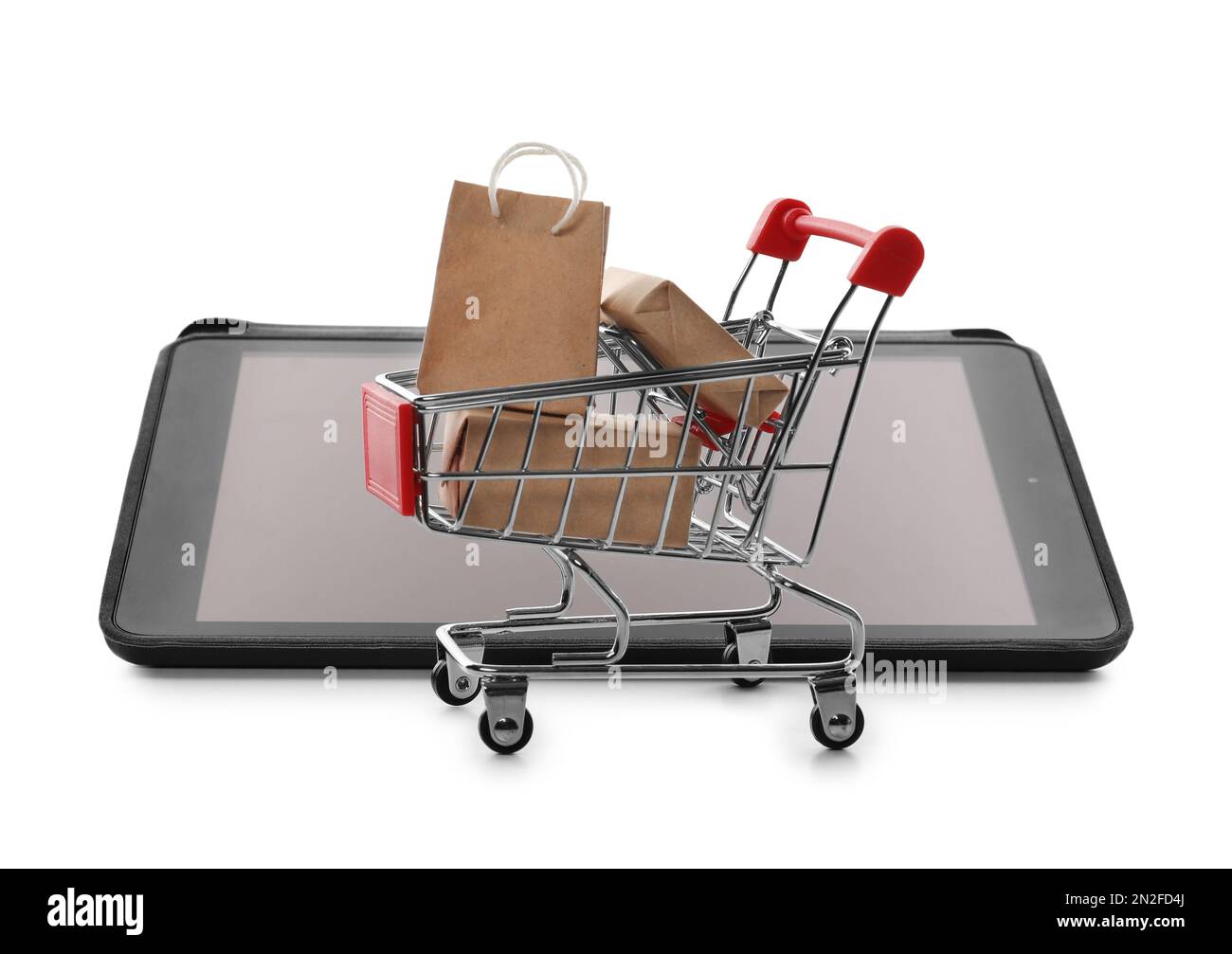 Internet shopping. Small cart with boxes and bag near modern tablet on ...