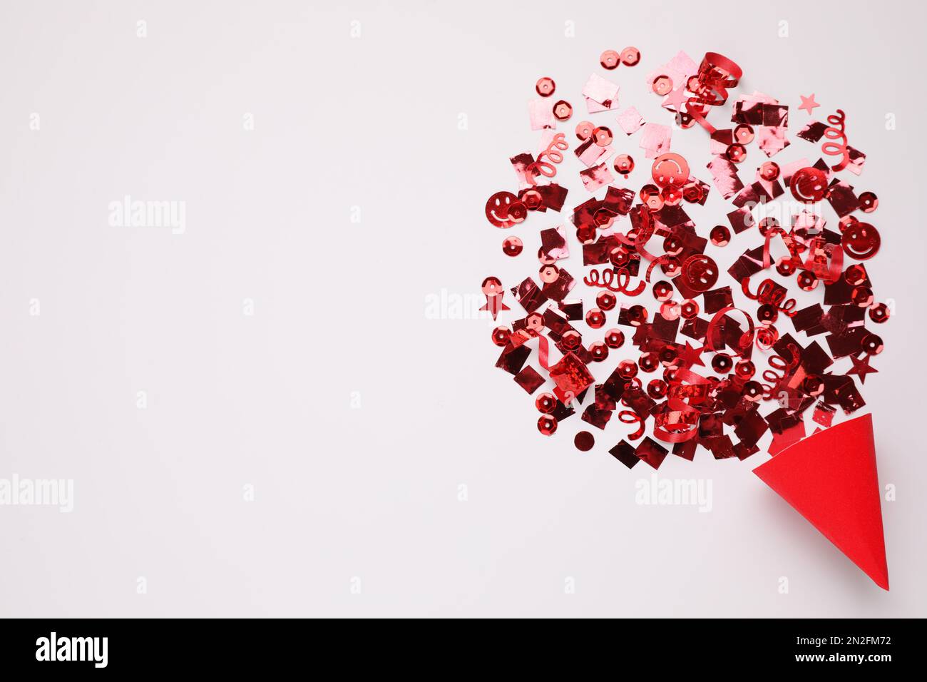 Shiny red confetti bursting out of party cracker on light background ...