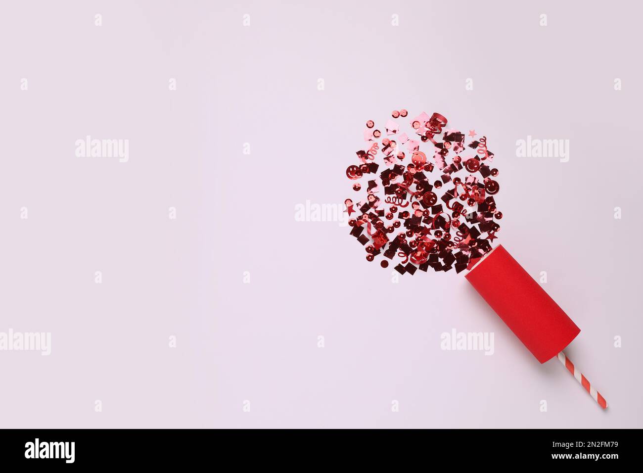 Shiny red confetti bursting out of party cracker on light background ...