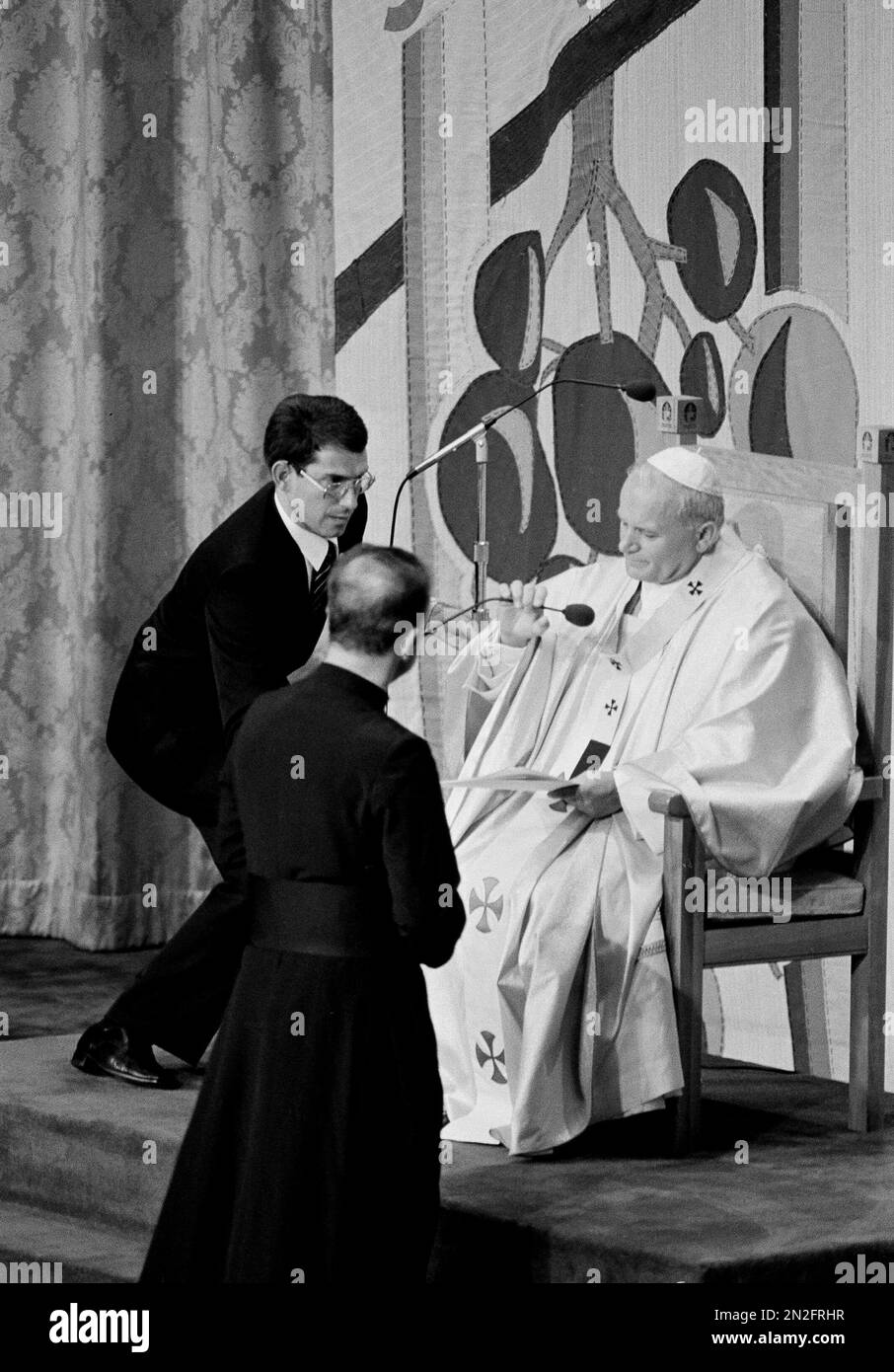 Pope John Paul II tries to adjust a microphone that failed during mass ...