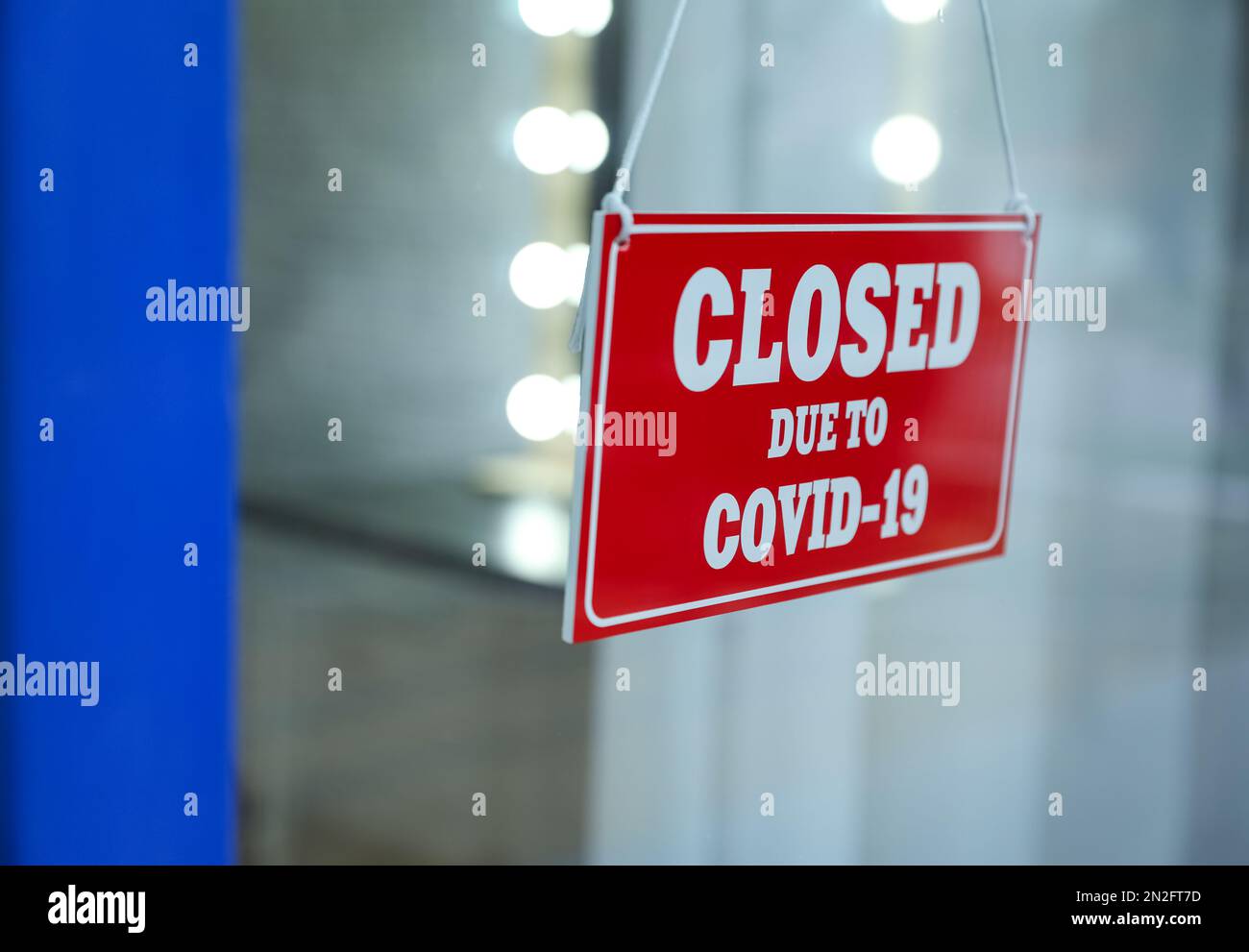 Red sign with text Closed Due To Covid-19 hanging on glass door ...