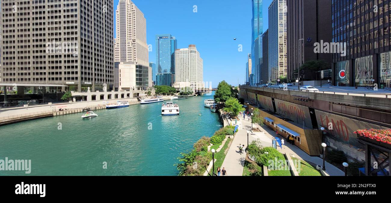A panoramic view of the Riverwalk of Chicago River boats with urban and ...
