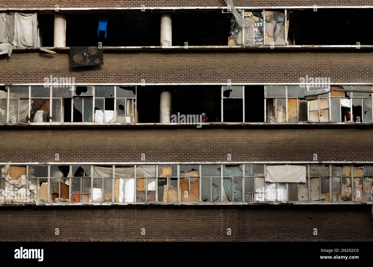 A man stand looks out from the window of a dilapidated building ...
