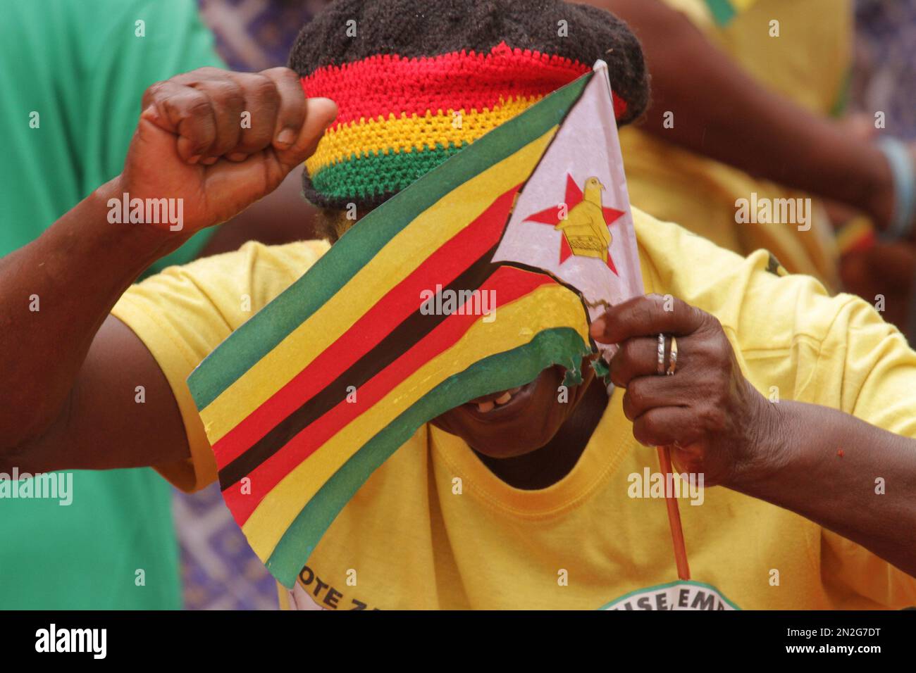 A woman celebrates while holding the Zimbabwean flag, as Zimbabwean ...