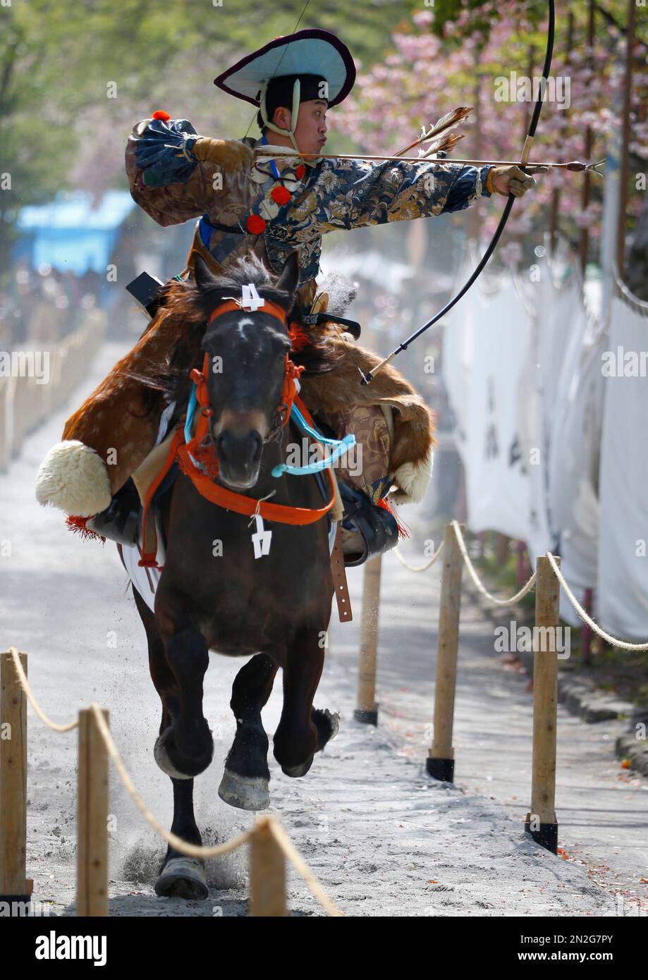 An archer in a samurai warrior costume aims at a target in the Asakusa ...