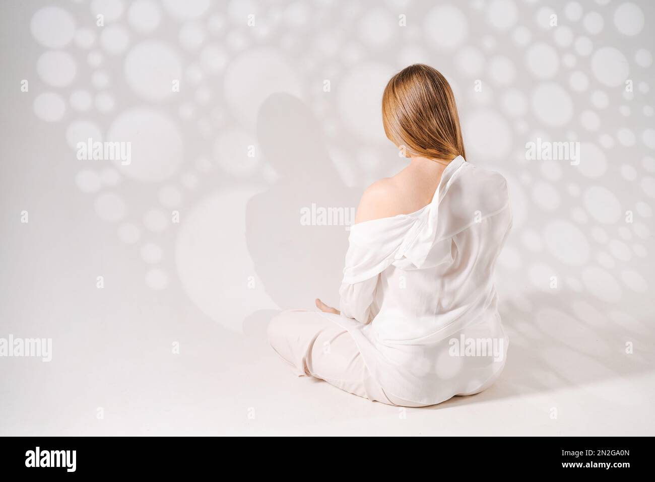 Depressed woman sits on floor on light background with soft, bright ...