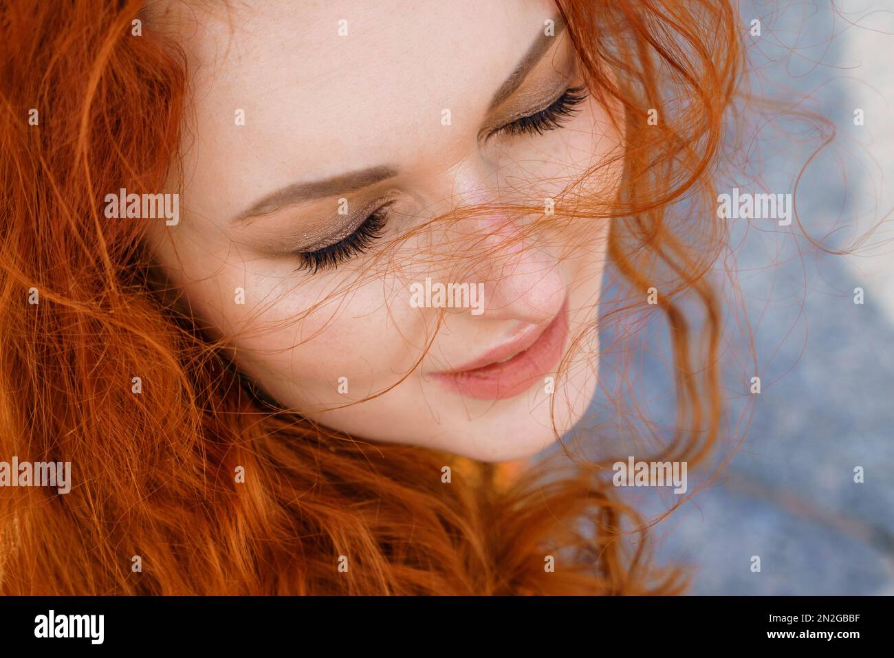 Close-up portrait young caucasian woman with red curly hair in red coat ...