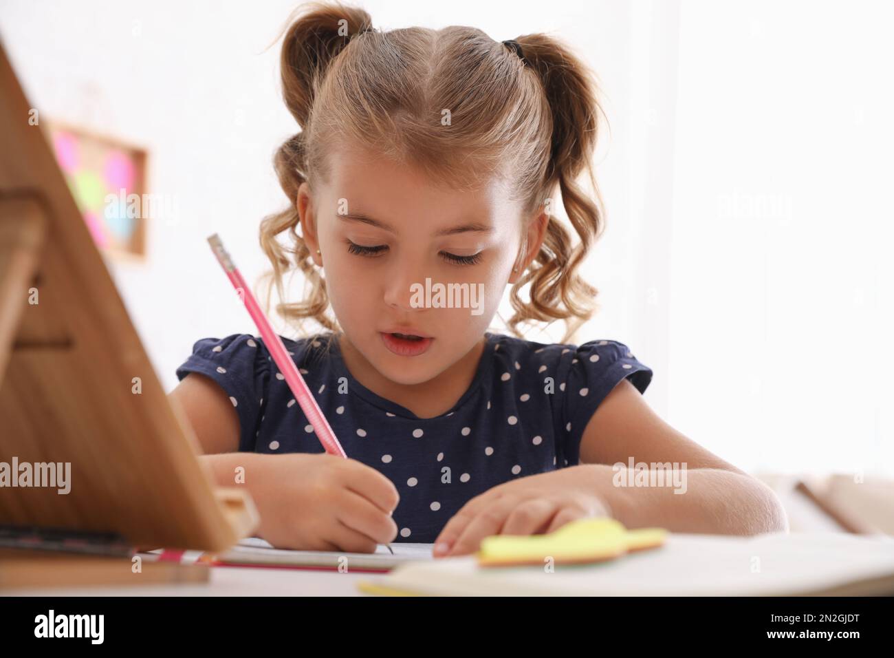 Cute little girl doing homework at table Stock Photo - Alamy