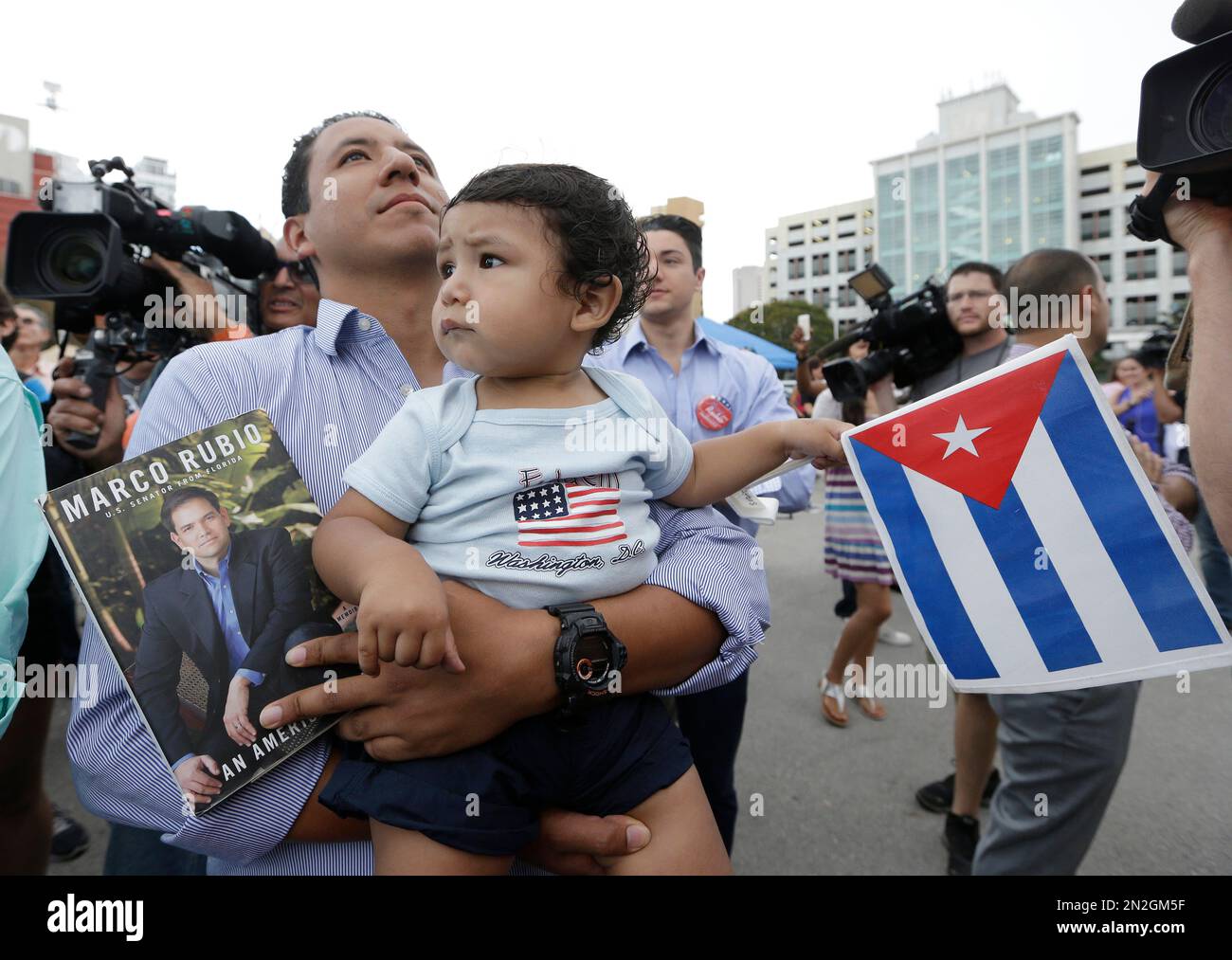 Carlos Avila, of Miami, left, holds his son Stephan who is holding a ...