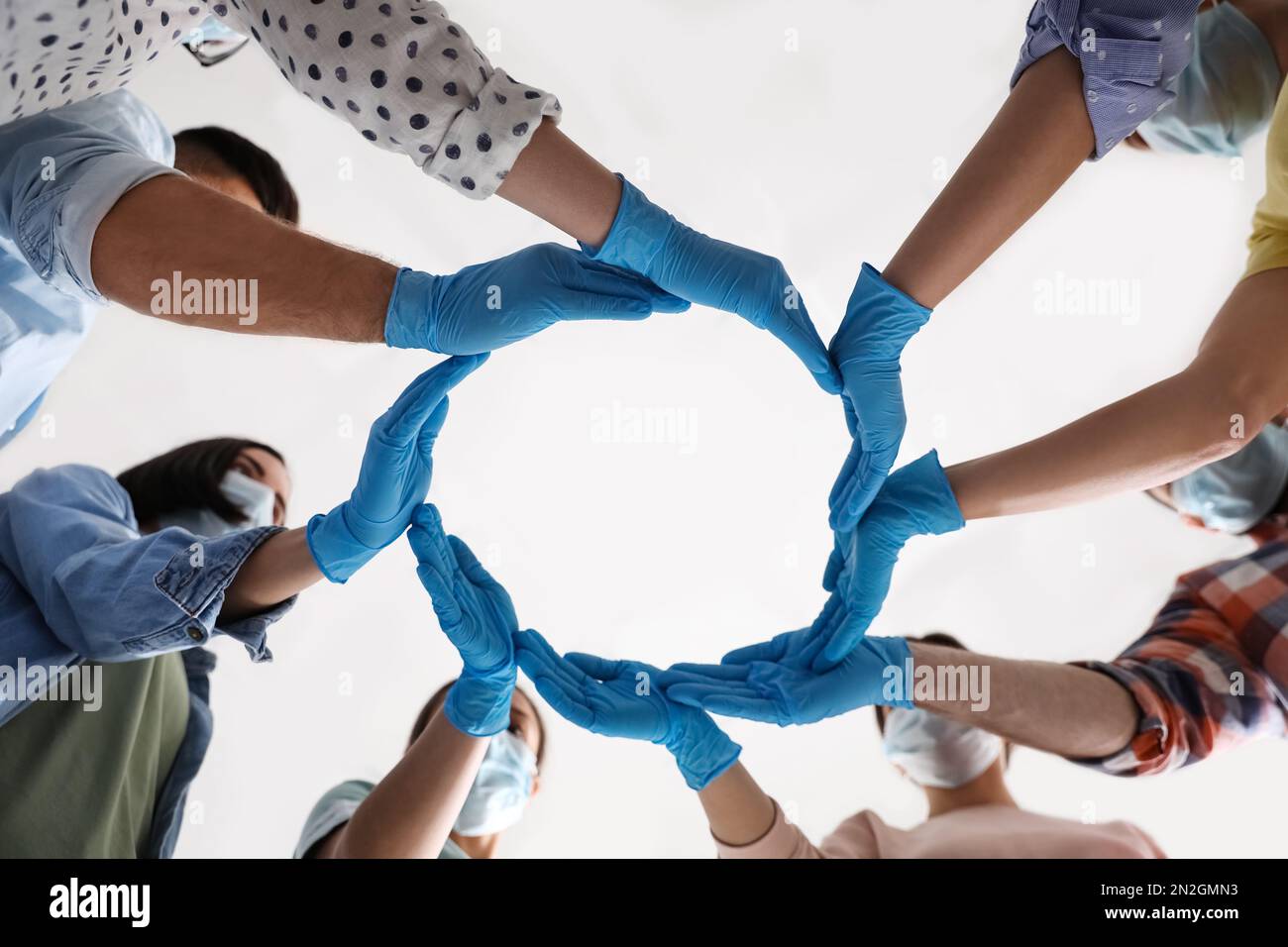 People in blue medical gloves showing circle with hands on light ...