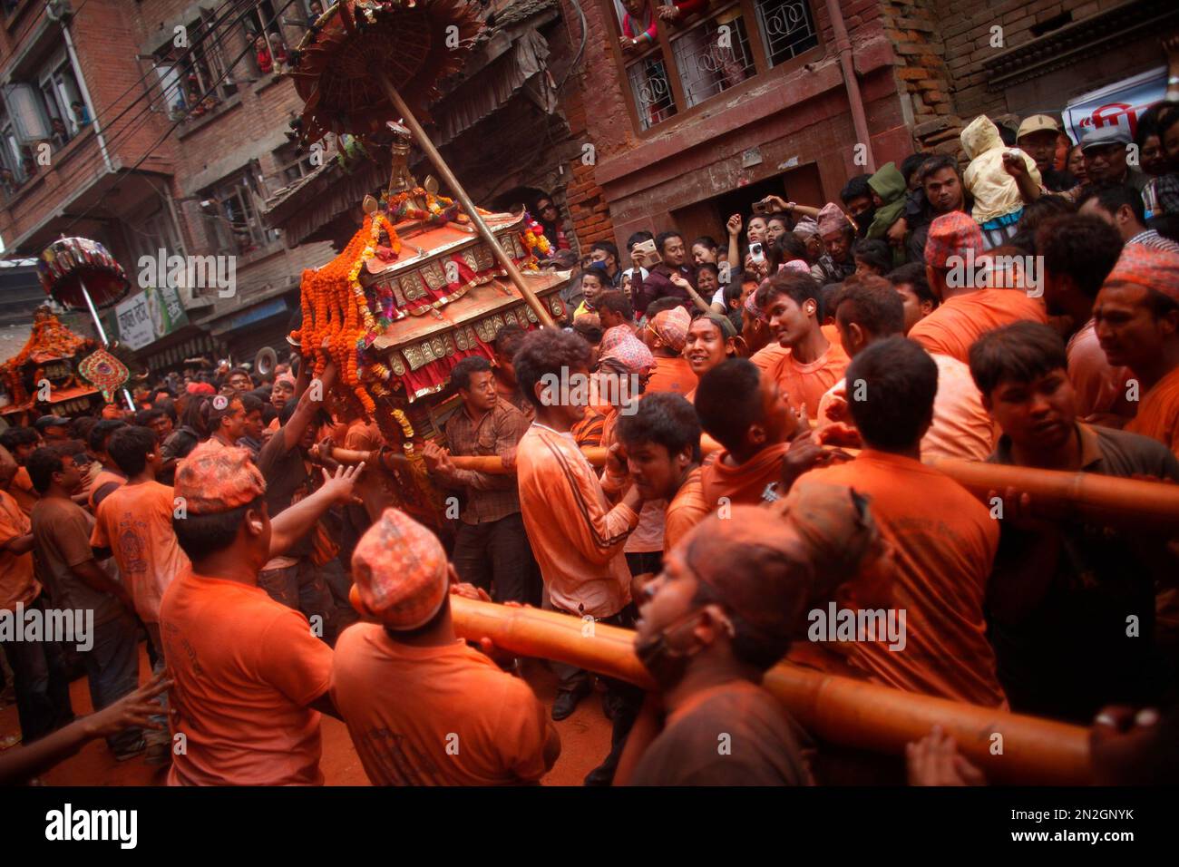 Nepalese devotees, covered in color vermilion powder, carry a palanquin ...
