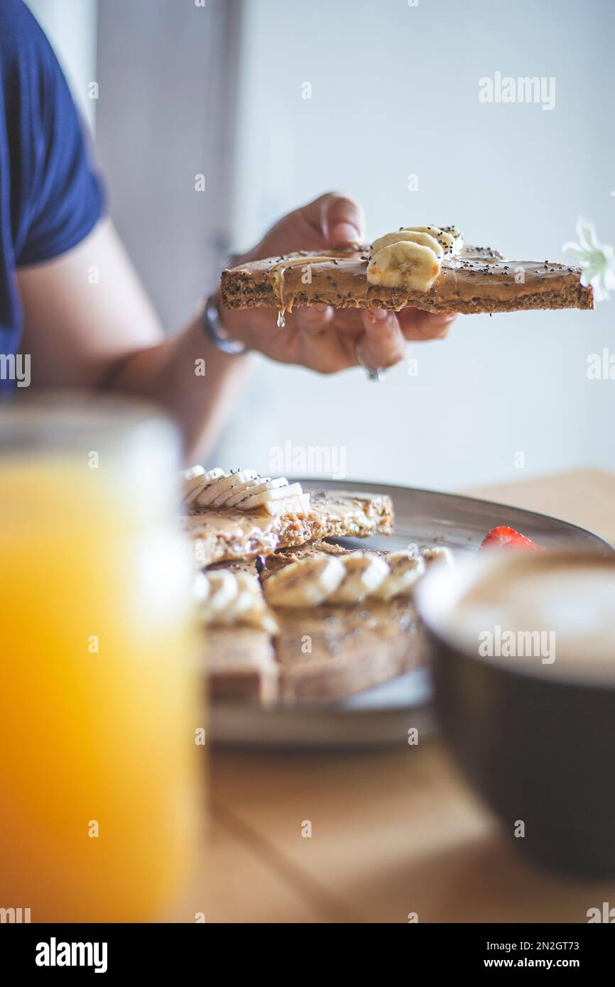 Woman's hand grabbing a peanut butter, banana and strawberry toast on a ...