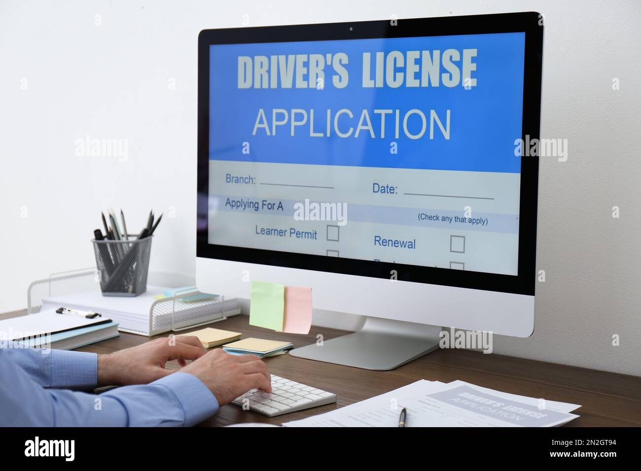 Man using computer to fill driver's license application form at table in office, closeup Stock ...
