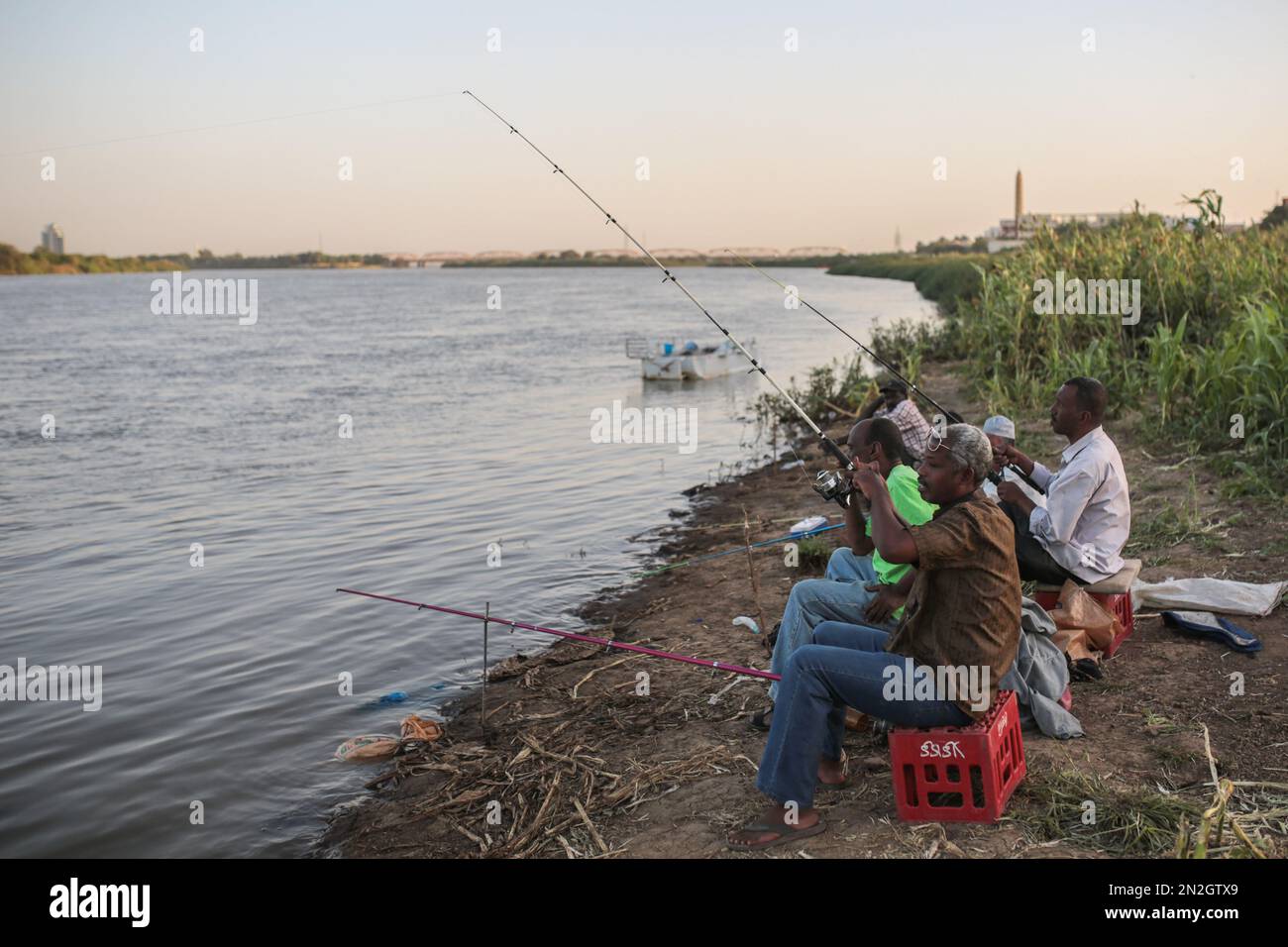 Sudanese men use fishing rods to catch fish in the Nile Rive, in ...