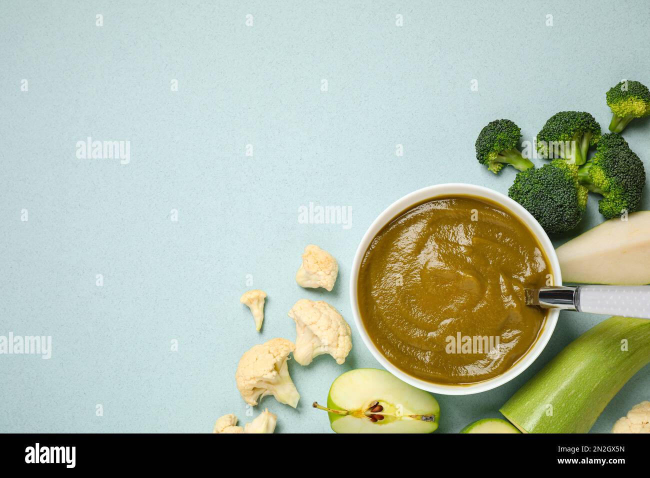 Healthy baby food and ingredients on light blue background. Space for ...