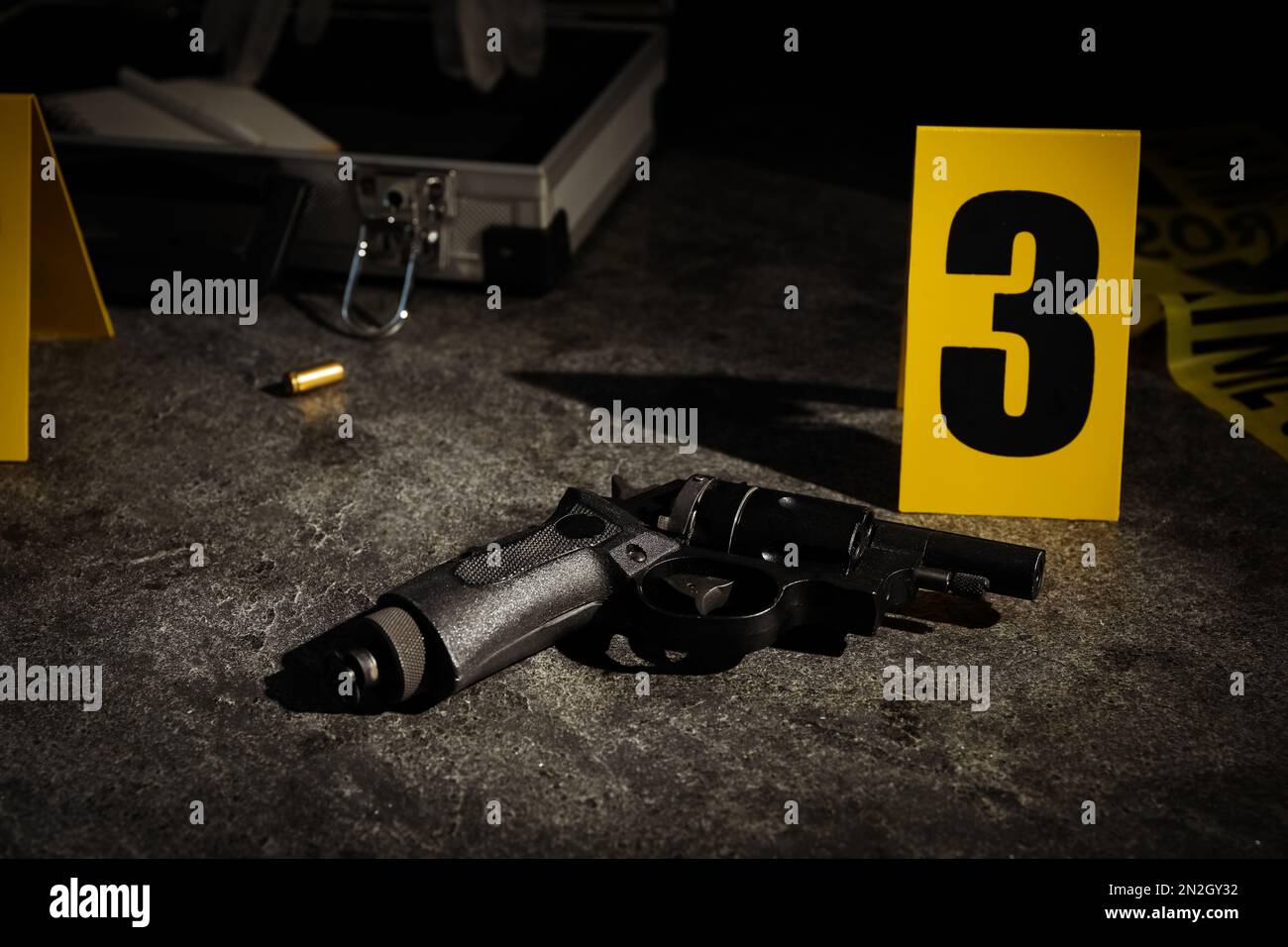 Shell casing, gun and crime scene marker on grey stone table Stock ...