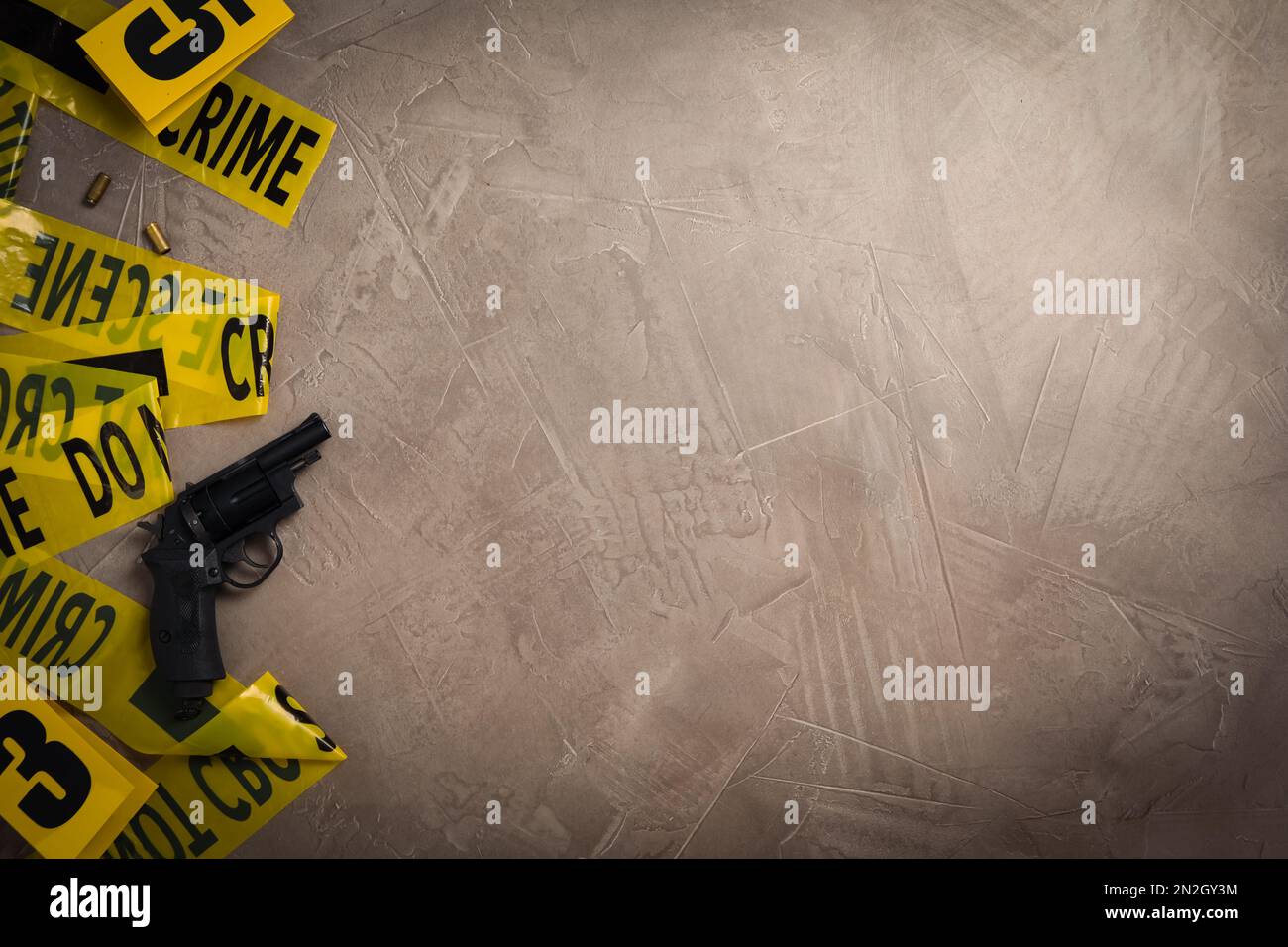 Flat lay with yellow tape, crime scene marker and gun on grey stone ...