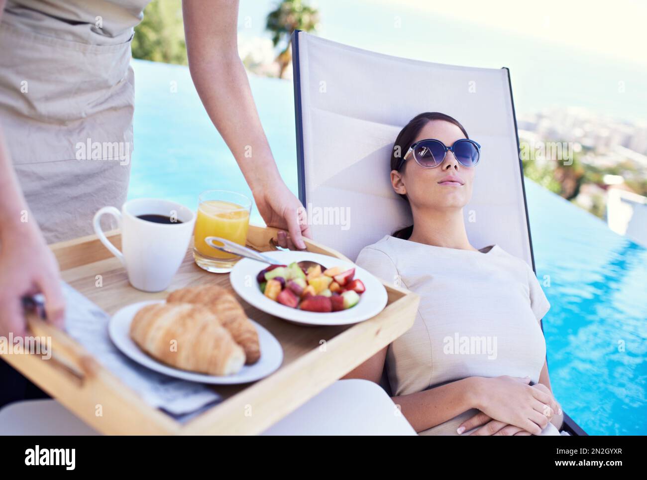 Relaxing while on holiday. A posh young woman being brought lunch by a ...