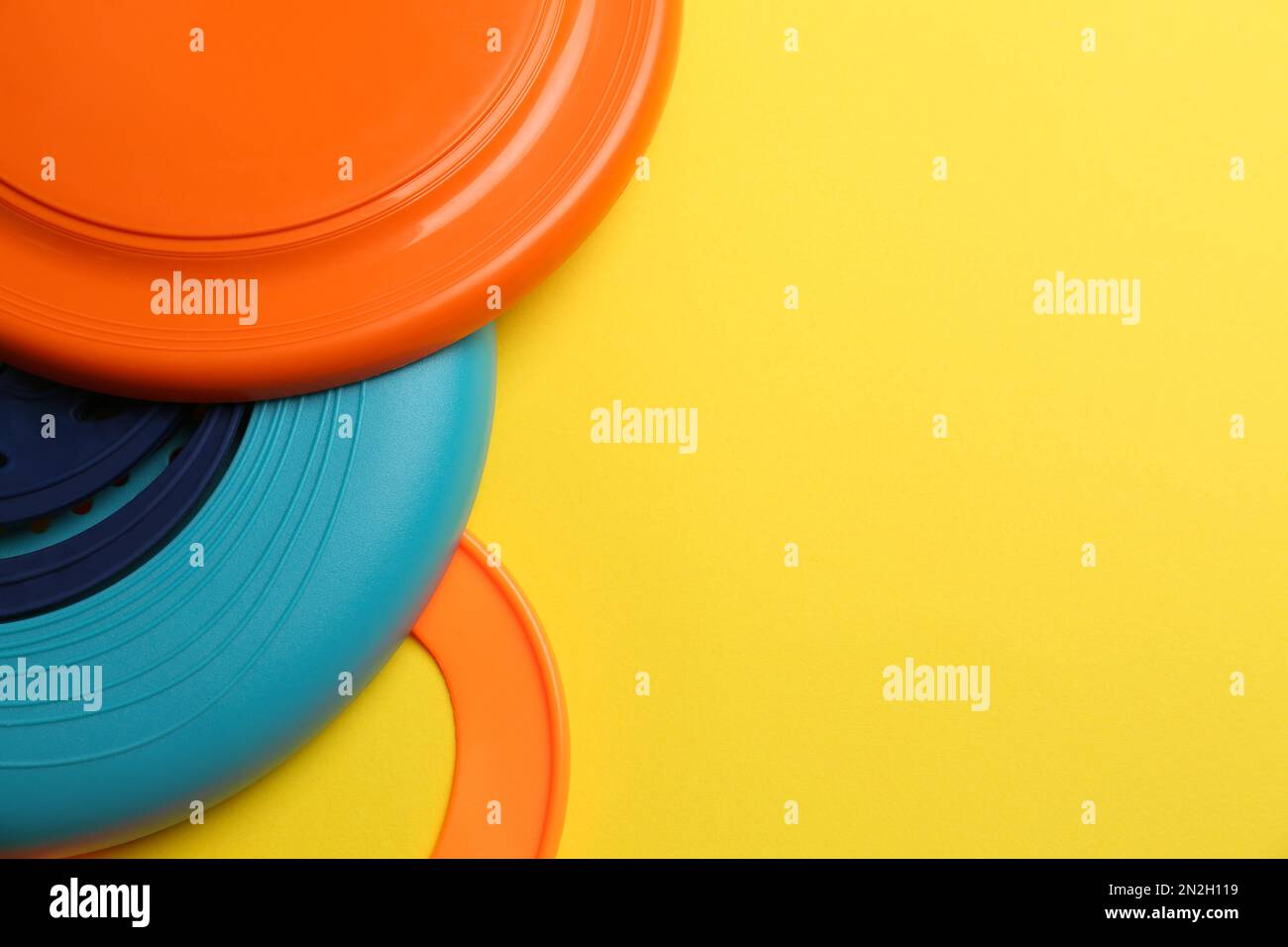 Plastic frisbee disks and ring on yellow background, flat lay. Space ...
