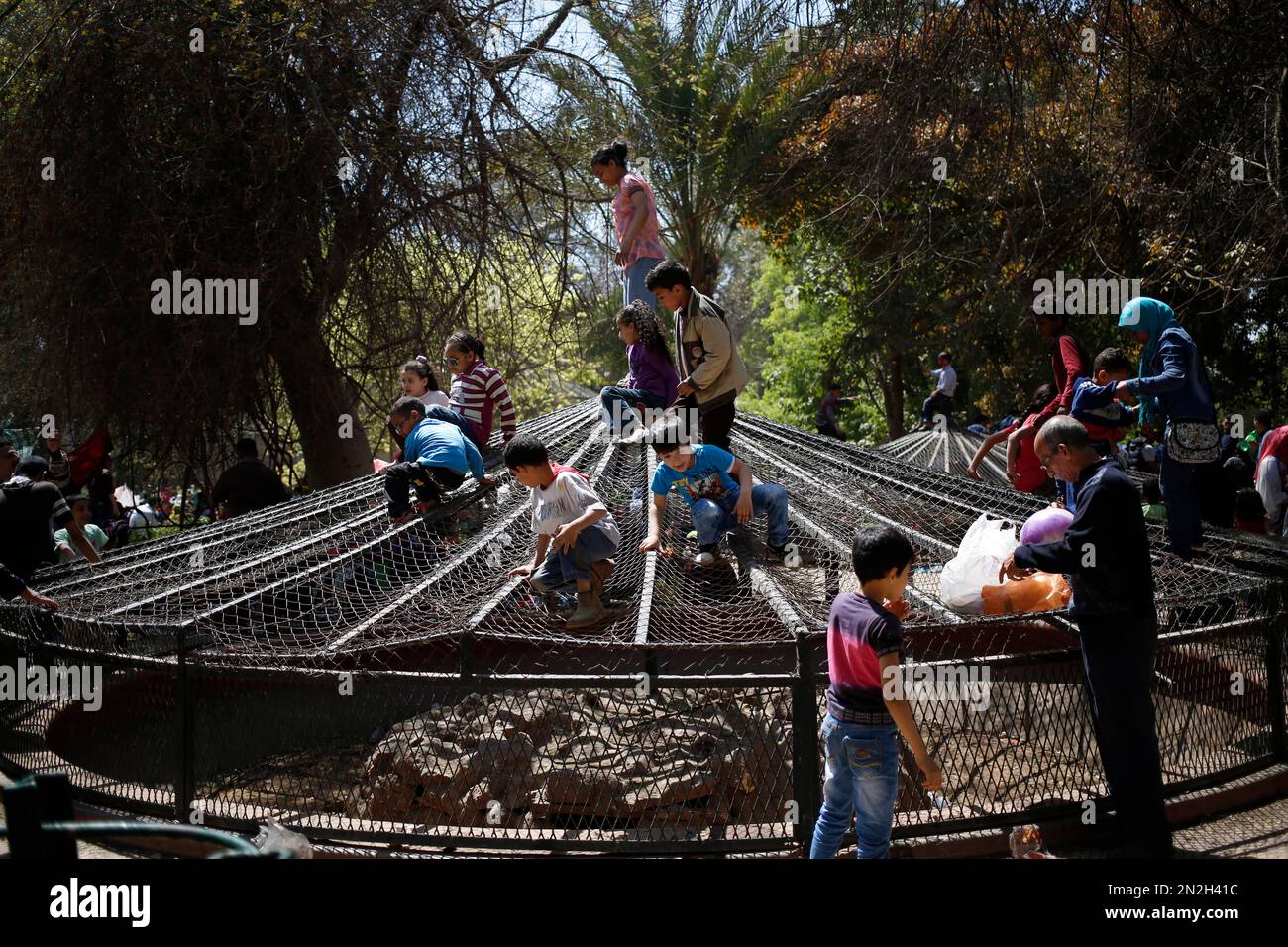 Egyptian children play on top of a cage at the Giza Zoo, as the country ...