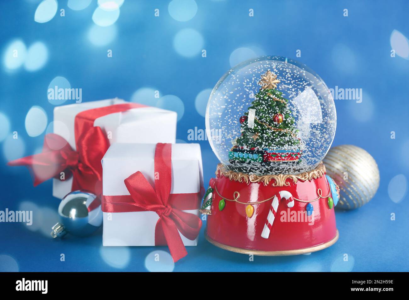 Beautiful Christmas snow globe, gift boxes and ornaments on blue ...