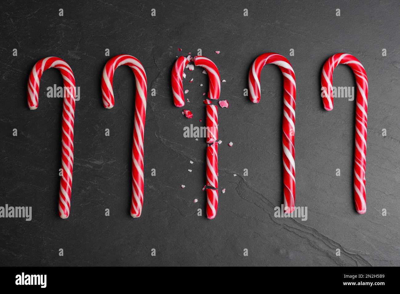 Crushed and whole Christmas candy canes on black background, flat lay ...
