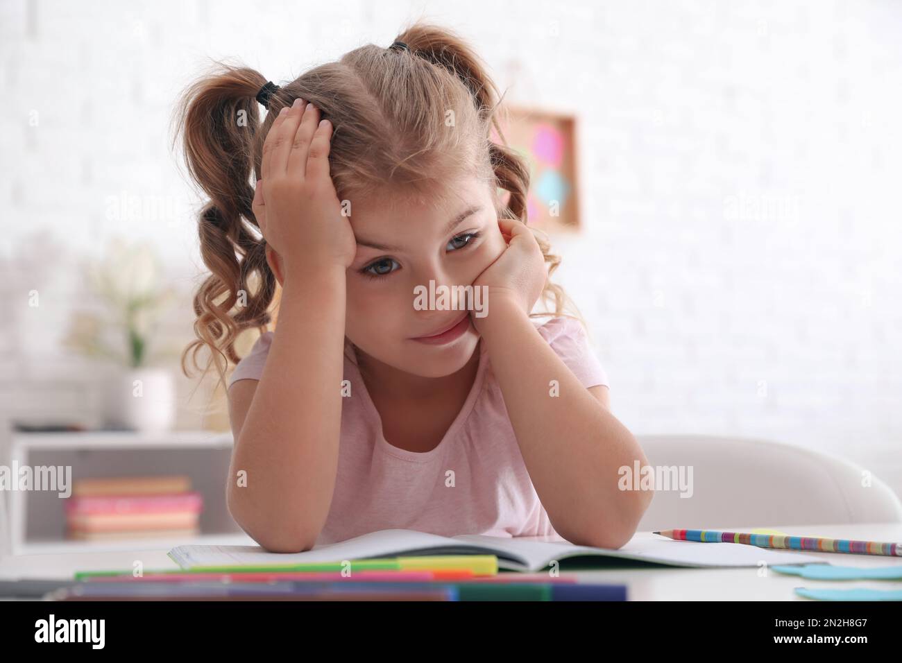 Tired little girl at table. Doing homework Stock Photo - Alamy
