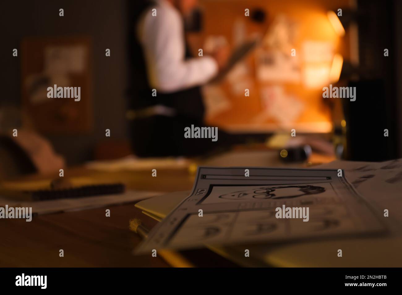 Paper with suspect's portrait on table in detective office, closeup ...