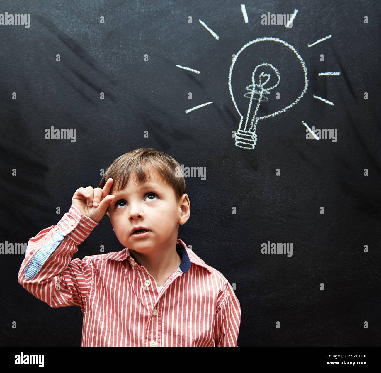 Wisdom begins with wonder. a young boy with a chalk drawing of a light ...