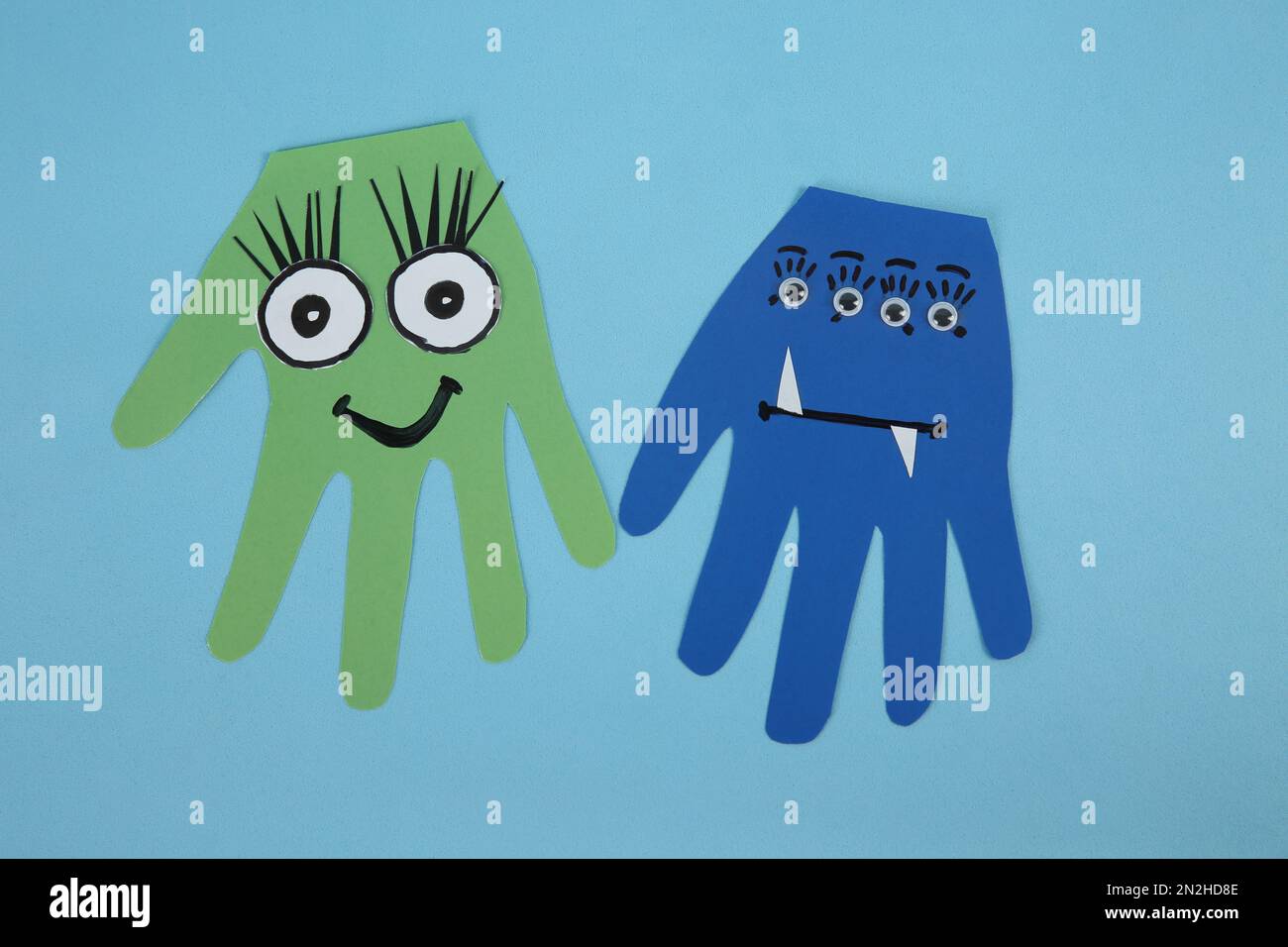 Funny hand shaped monsters on light blue background, flat lay ...