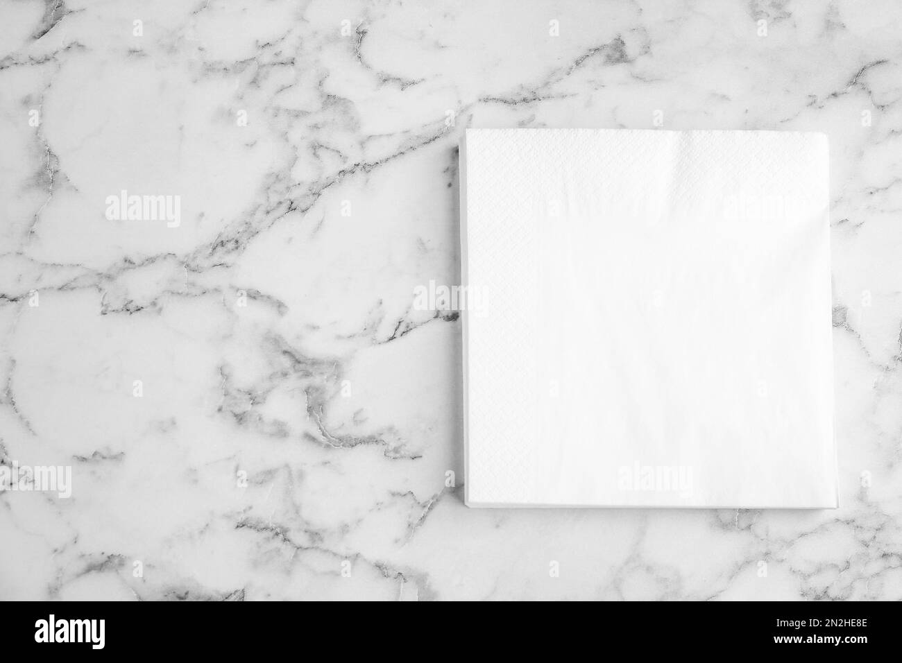 Stack of clean paper tissues on white marble table, top view. Space for ...
